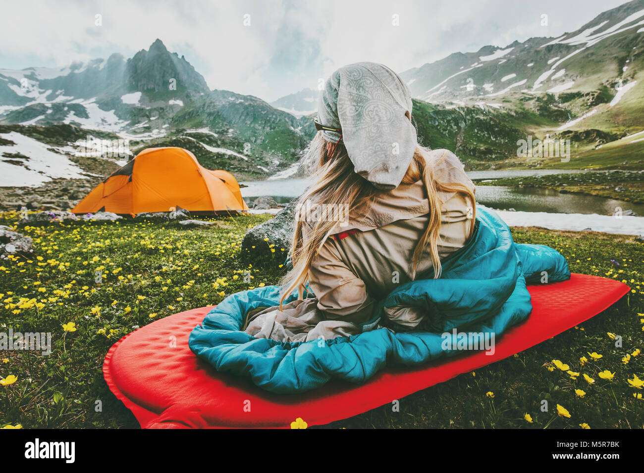 Woman relaxing in sleeping bag on red mat camping travel vacations in ...