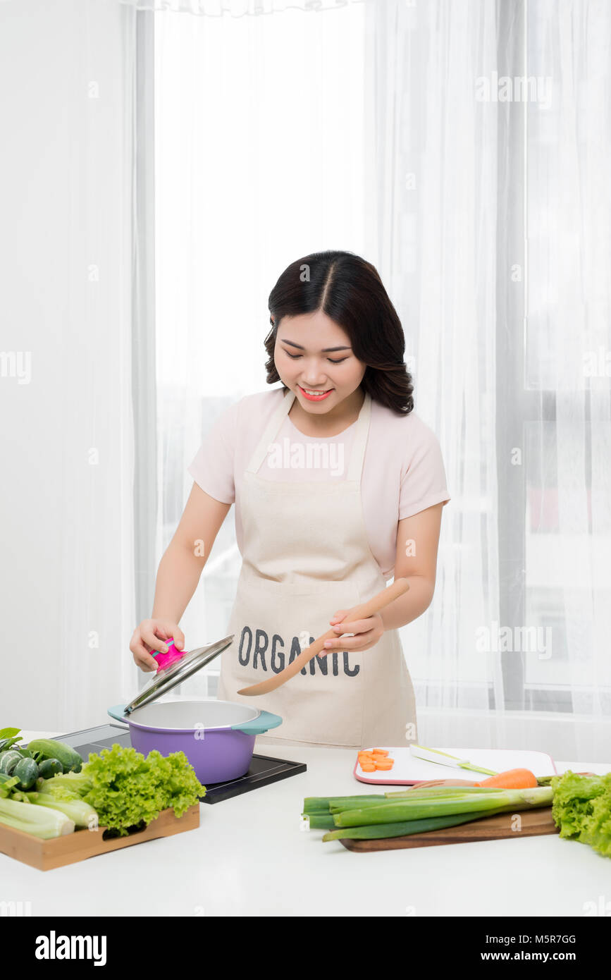 Healthy food. Asian woman cooking in the kitchen with wooden spoon ...