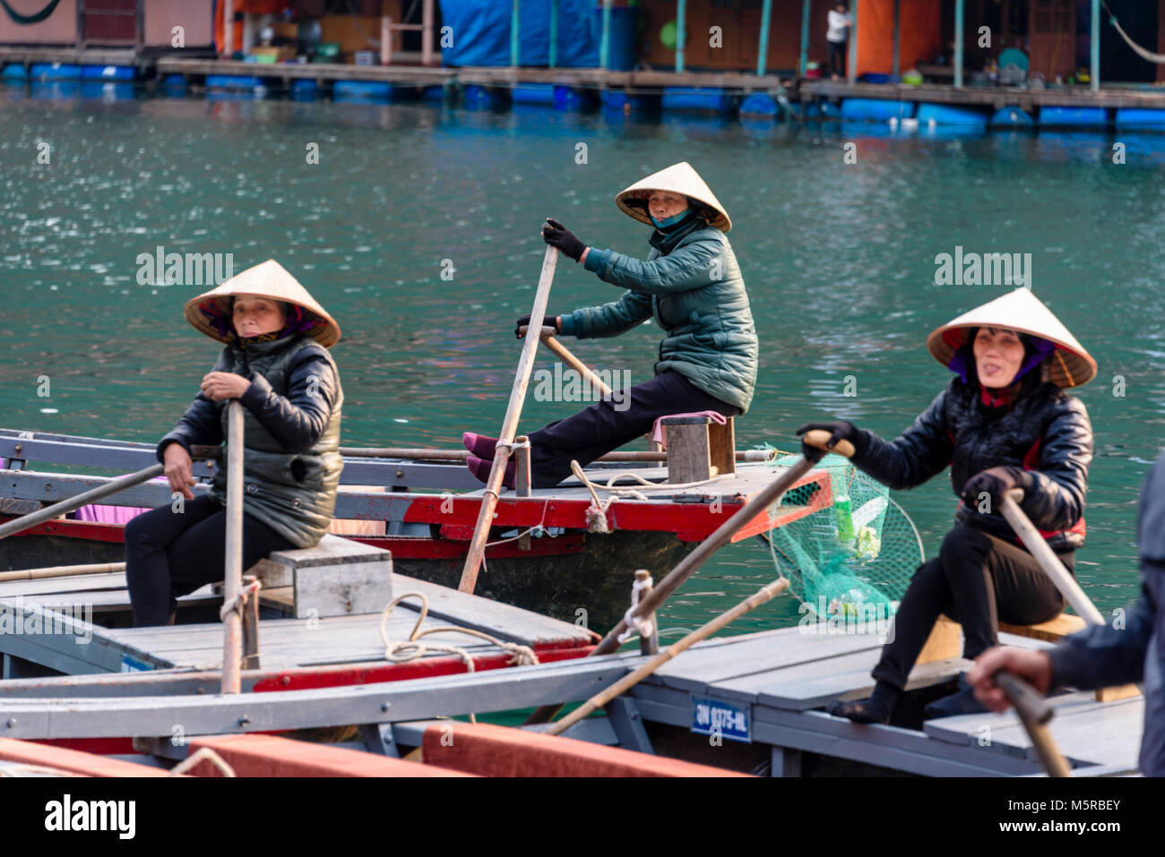 Vietnamese women wearing traditional bamboo conical hats in a rowing ...