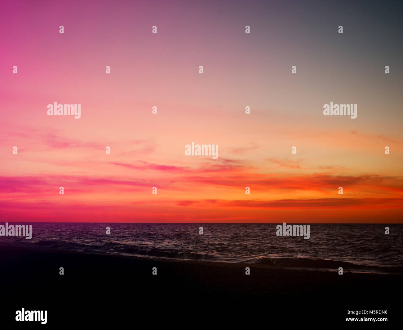 Orange and pink sunset sky over the beach Stock Photo - Alamy