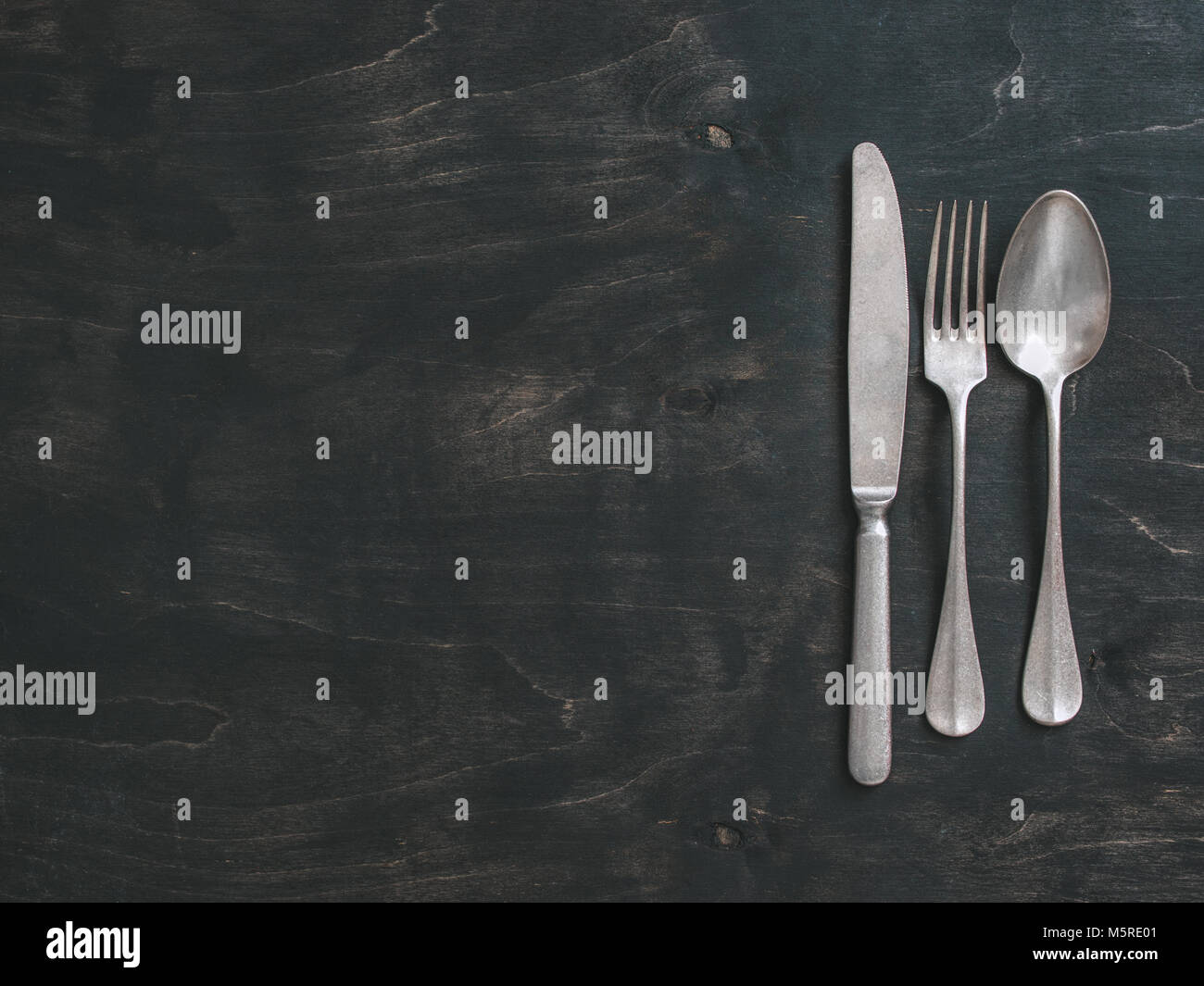 Vintage cutlery over dark background. Old tablespoon, fork and knife on ...