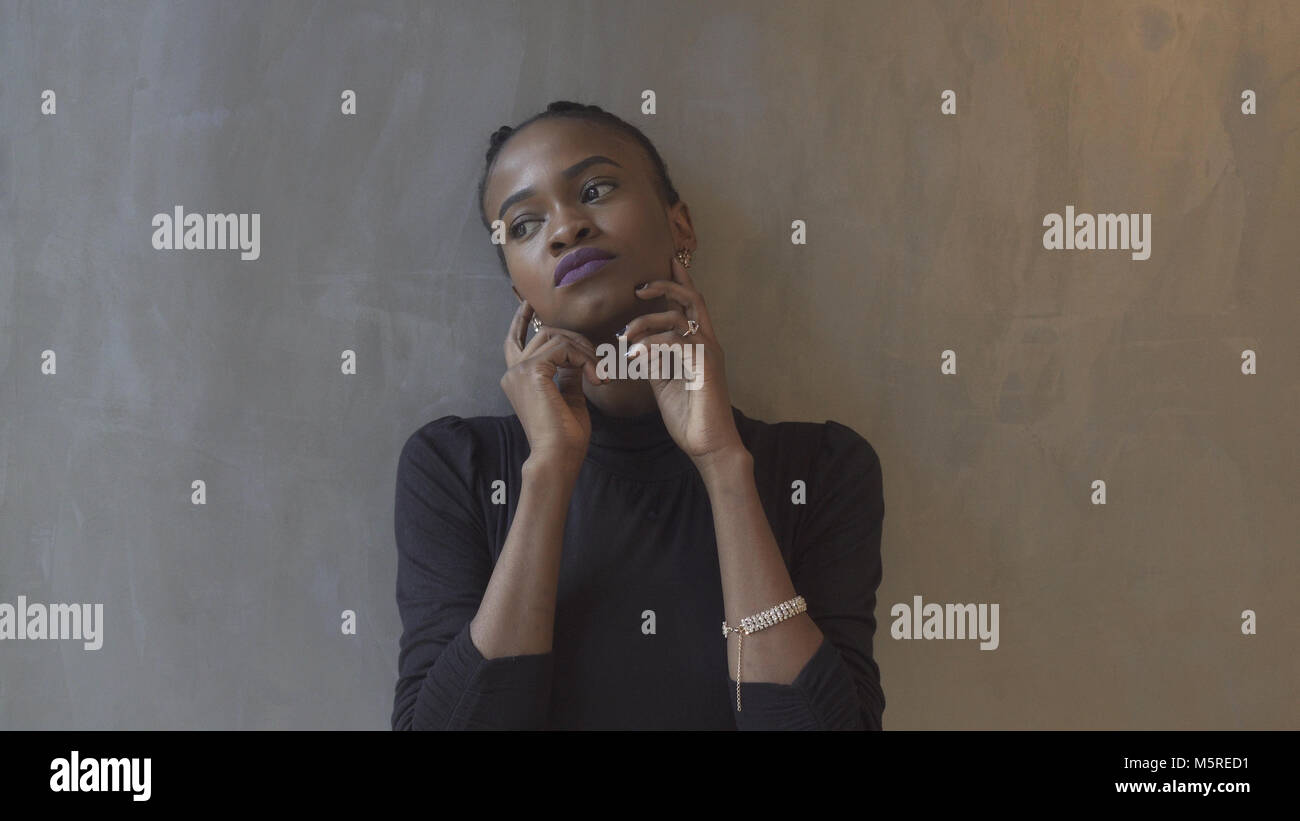Portrait of the young upset african woman in black dress looking aside ...