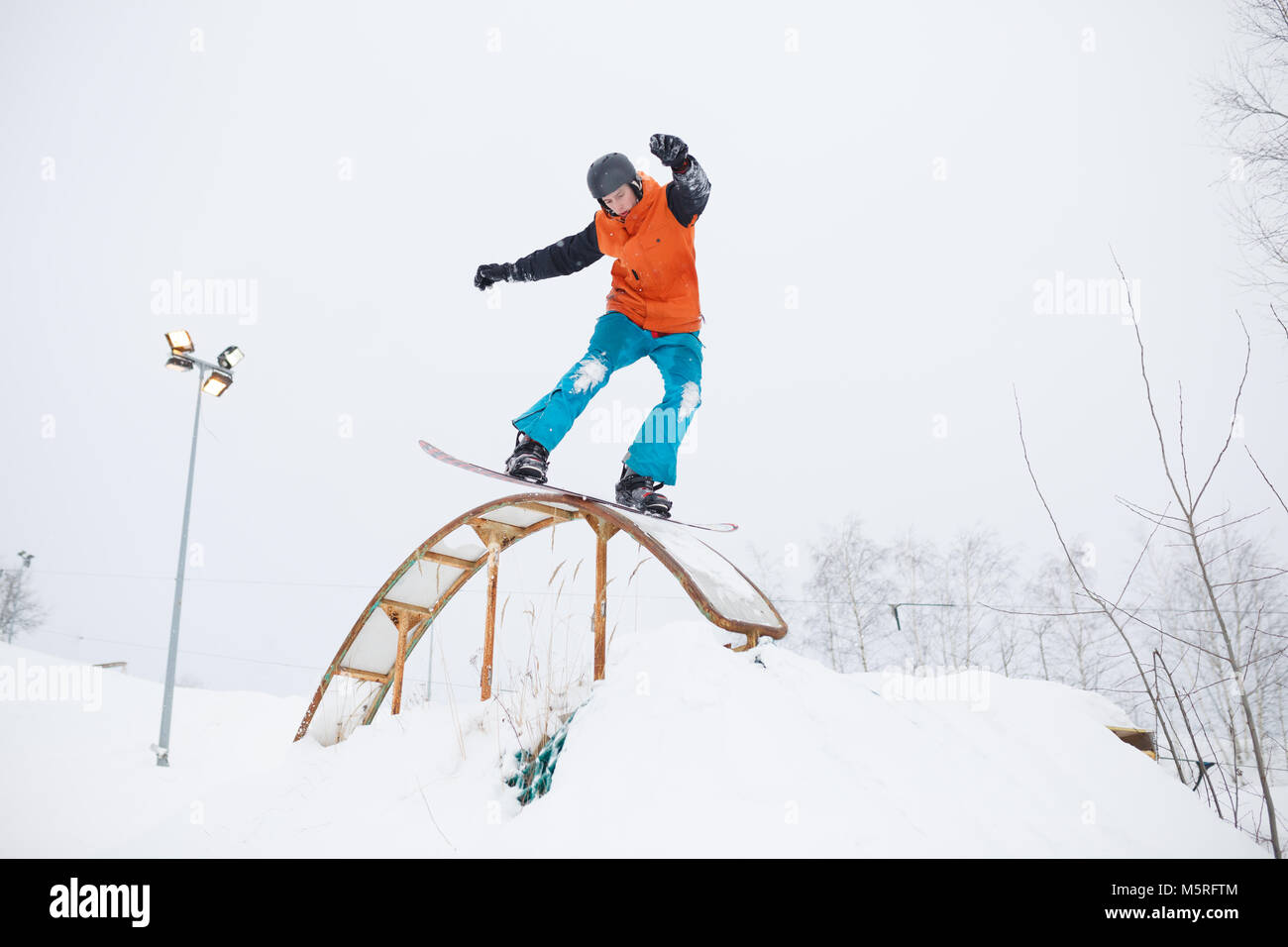 Photo of athlete skating on snowboard with springboard against ...