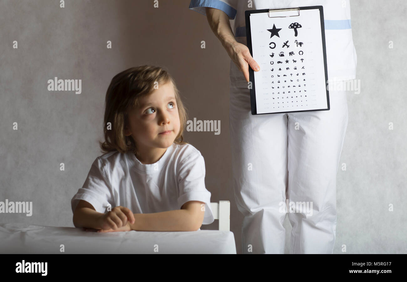Ophthalmologist checks vision of 5 years old boy by means of eye chart ...