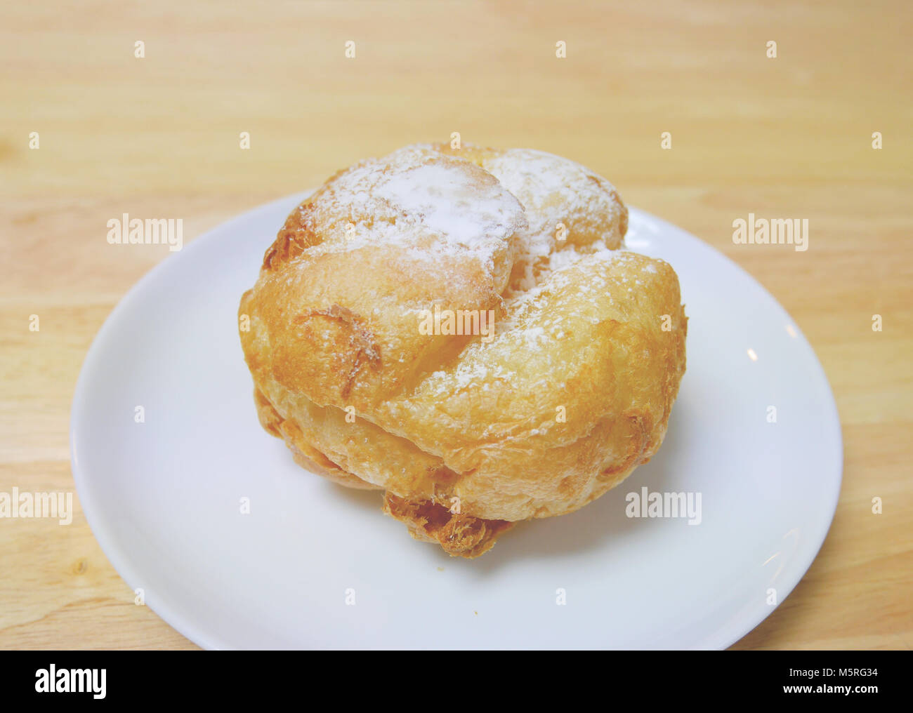 Whole homemade Japanese choux cream puff with icing on a small white ...