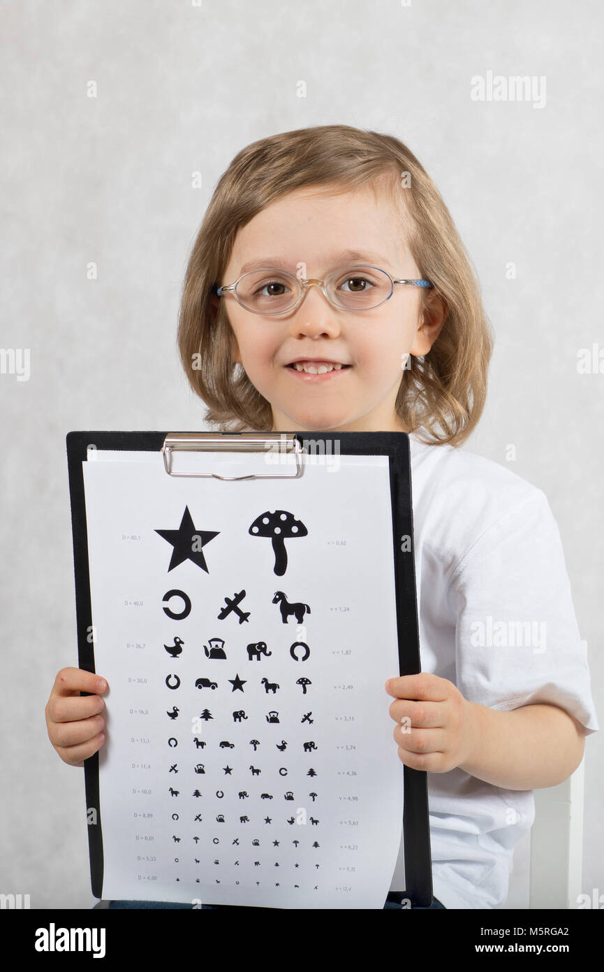 Ophtalmologist checks vision of 5 years old boy by means of eye chart ...