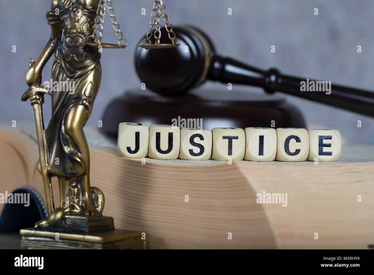 Word JUSTICE composed of wooden letters. Statue Themis and judge's ...