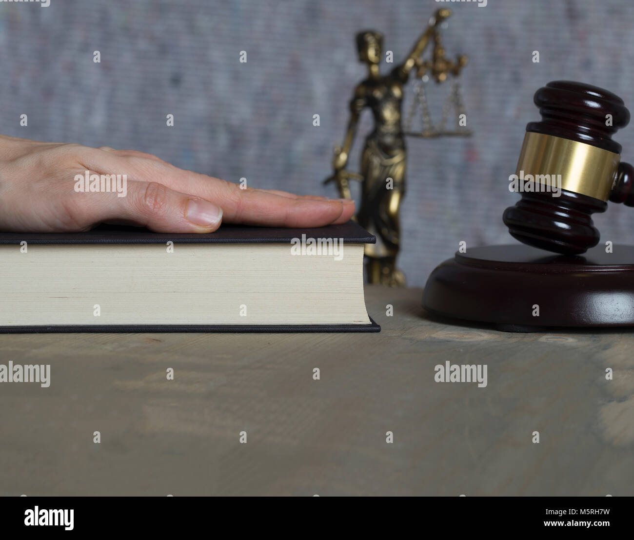 Witness's hand on a bible. Statue of Themis and judge's gavel in the ...