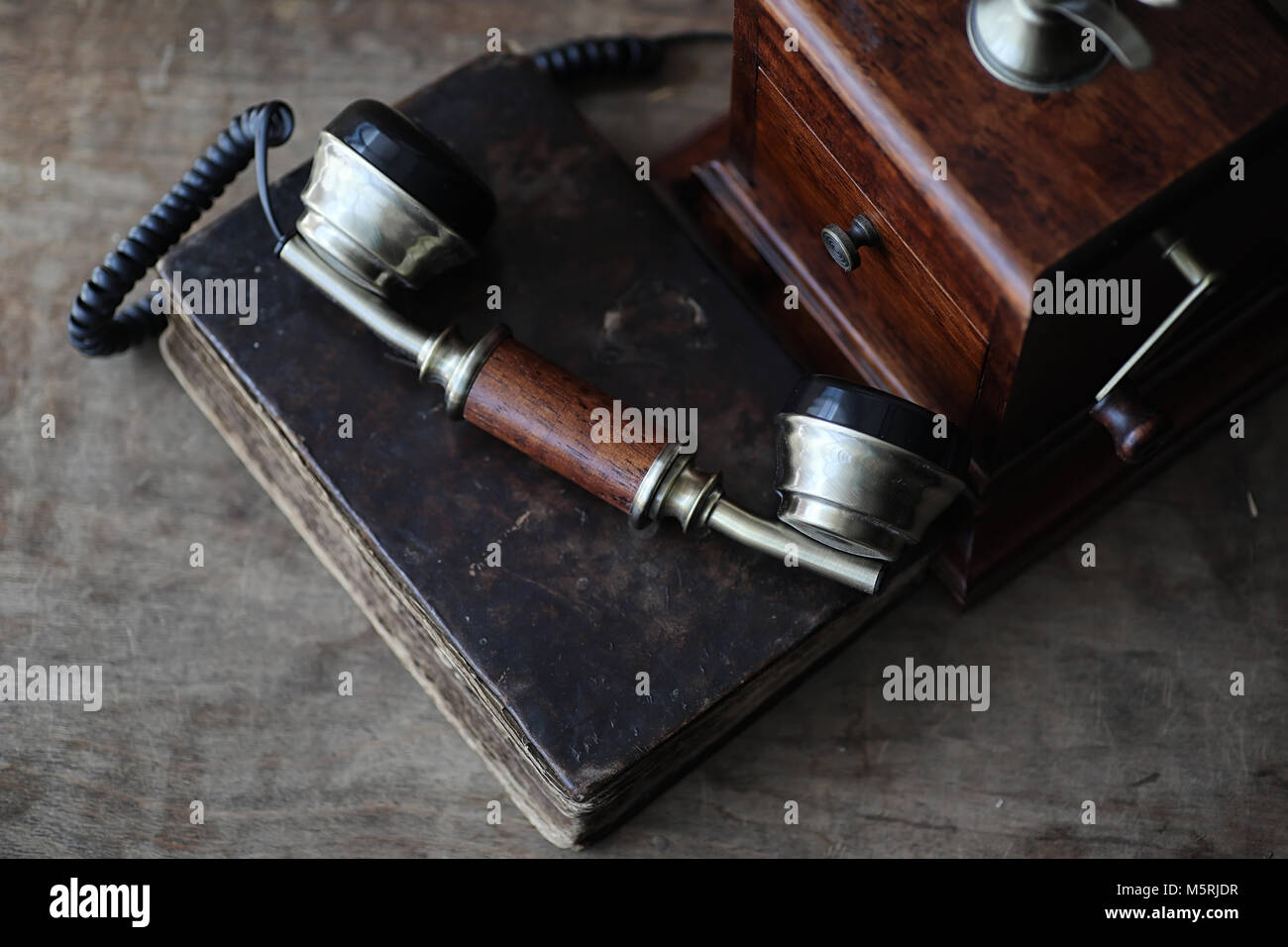 Old telephone and retro book on a wood Stock Photo - Alamy