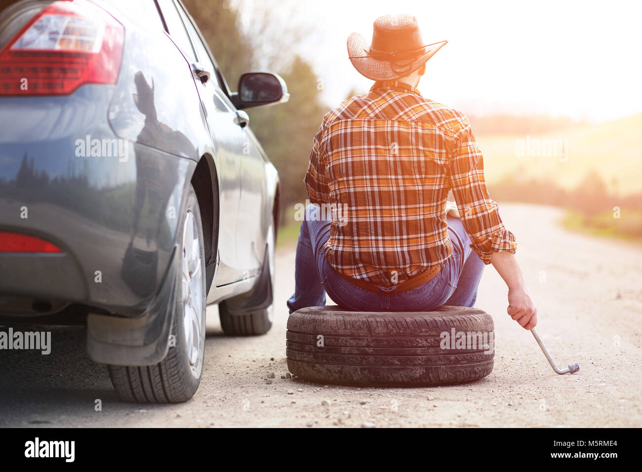 Man is sitting on the road by the car Stock Photo - Alamy