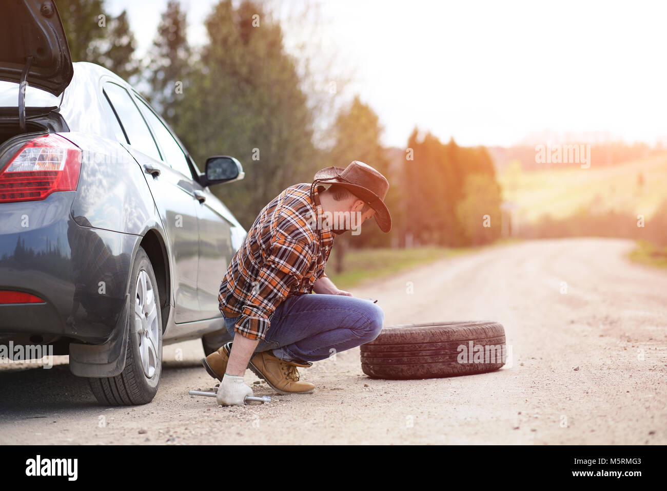 Man is sitting on the road by the car Stock Photo - Alamy