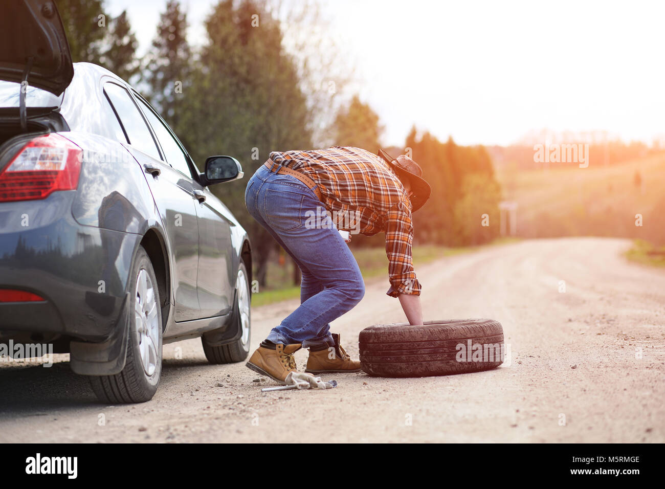 Man is sitting on the road by the car Stock Photo - Alamy