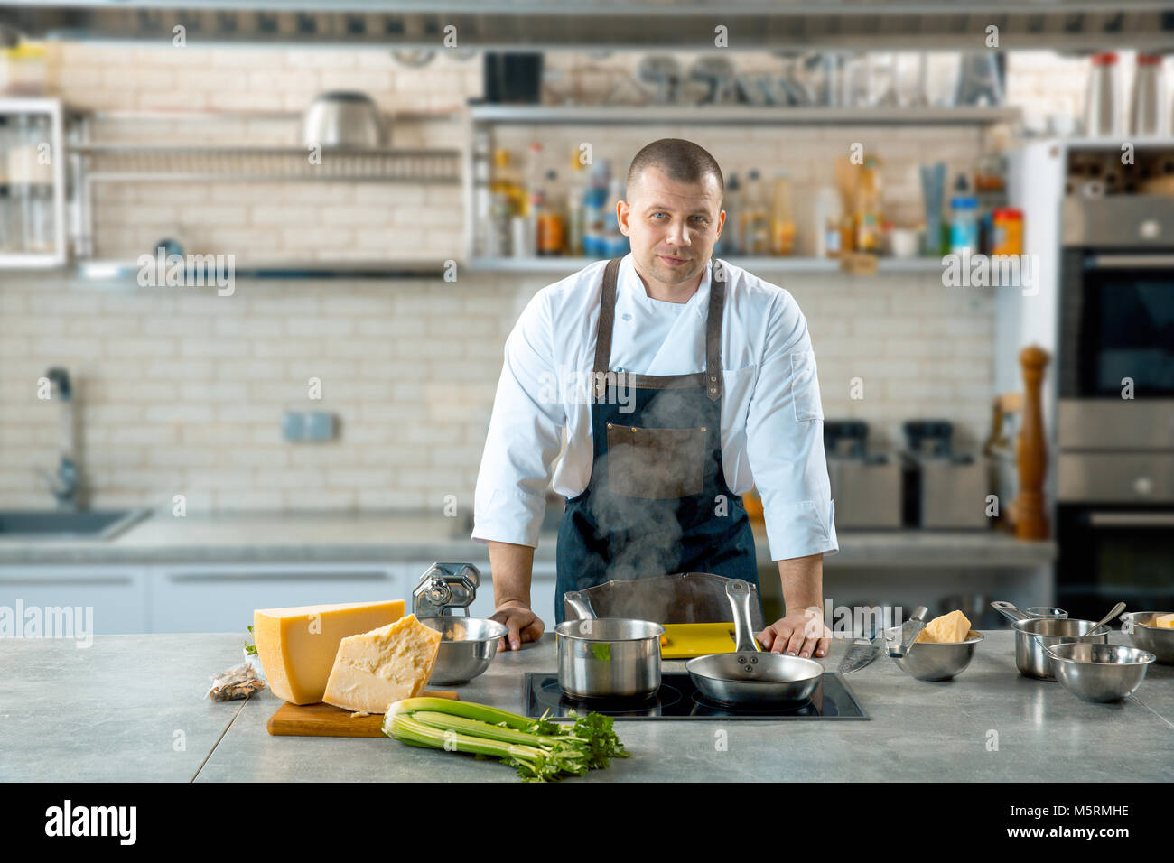 Handsome male chef in the kitchen interior. the cook is getting ready ...