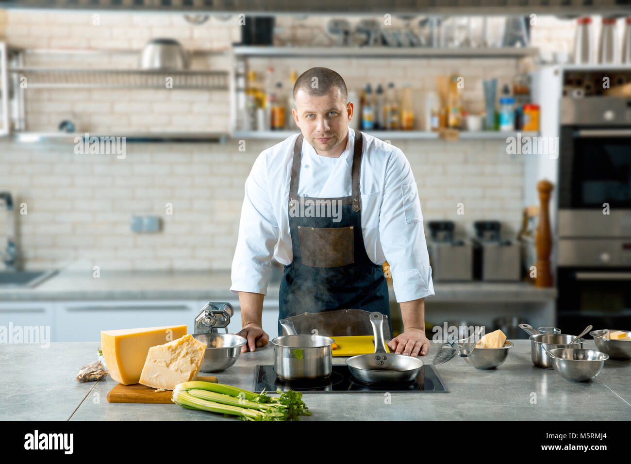 Handsome male chef in the kitchen interior. the cook is getting ready ...