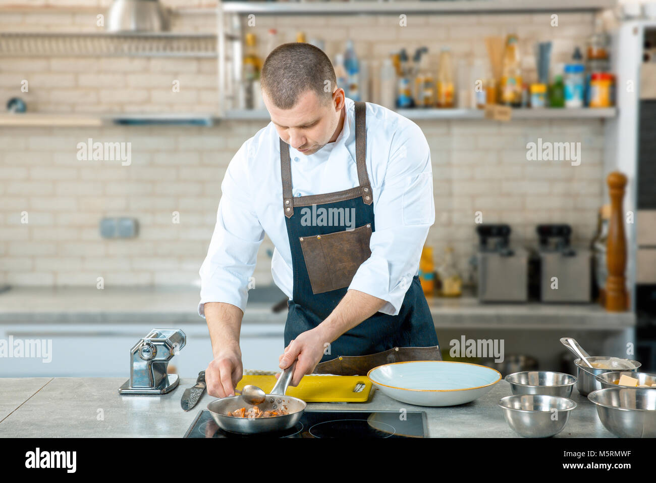 Chef holding frying pan. Chef is stirring dish in frying pan at ...
