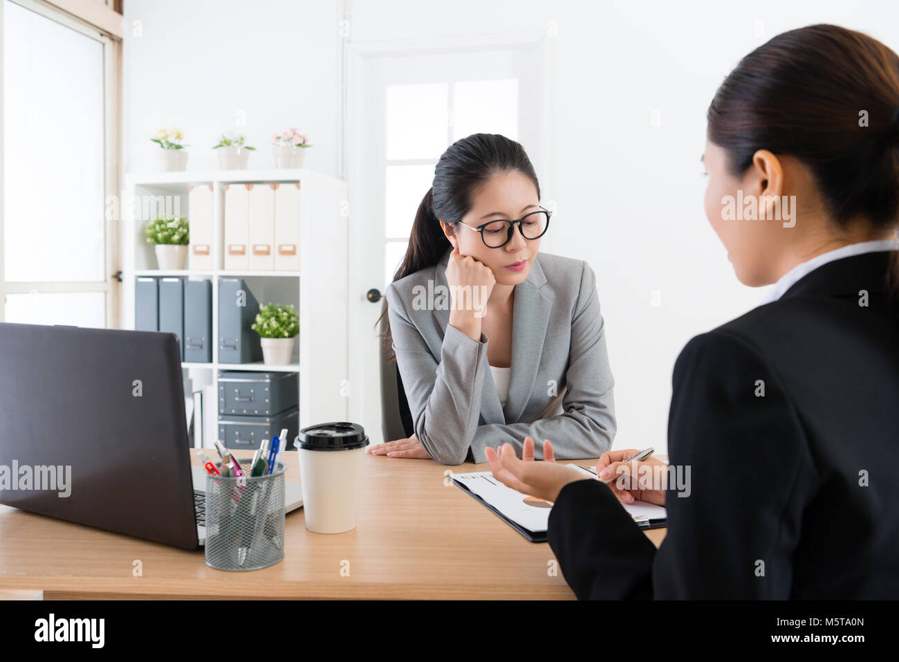 Asian businesswoman conducting a job interview seated at her desk in ...