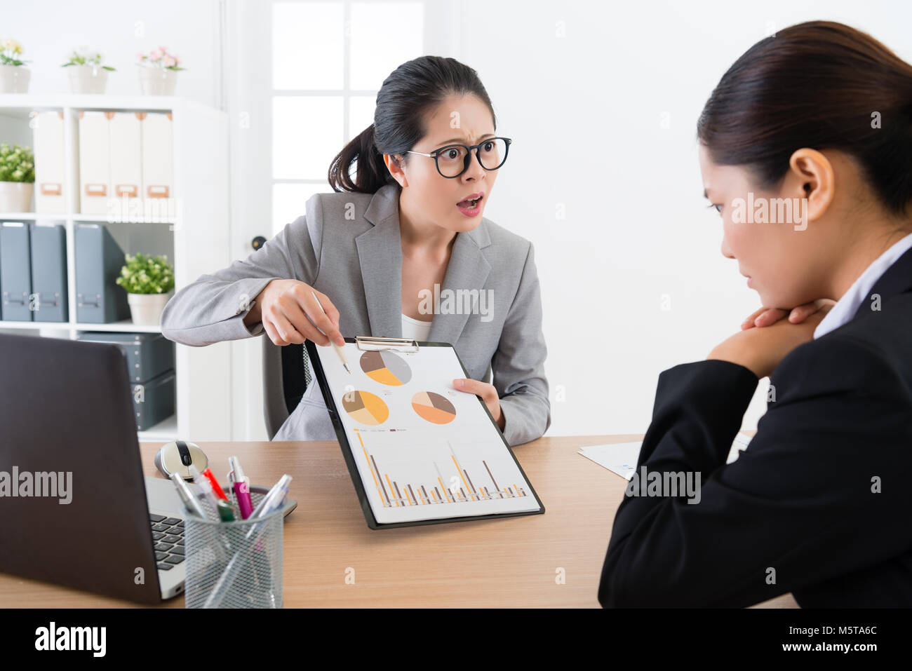 A strict asian business supervisor showing teaching displaying the ...