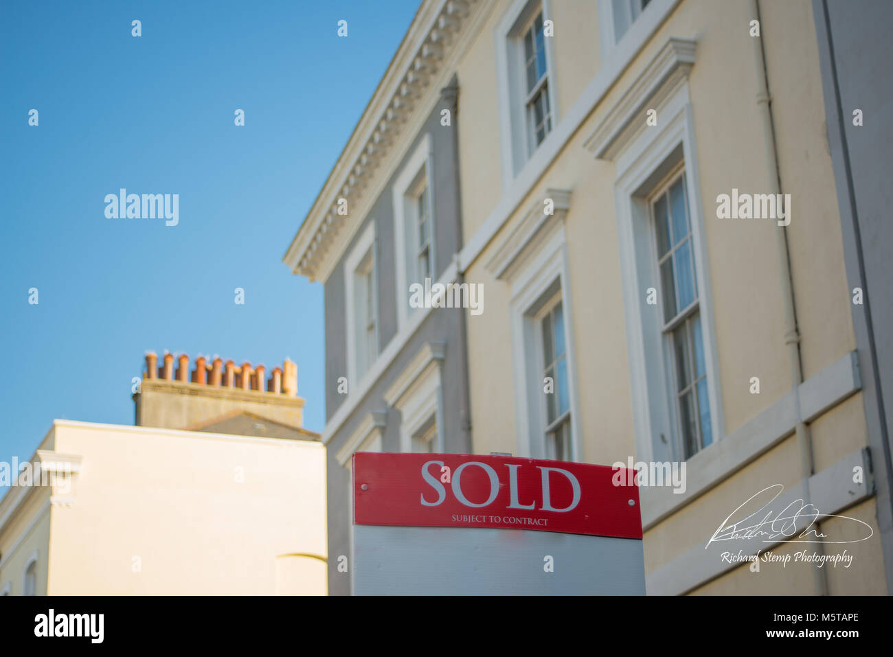 Sold sign in foreground with town houses in background Stock Photo - Alamy