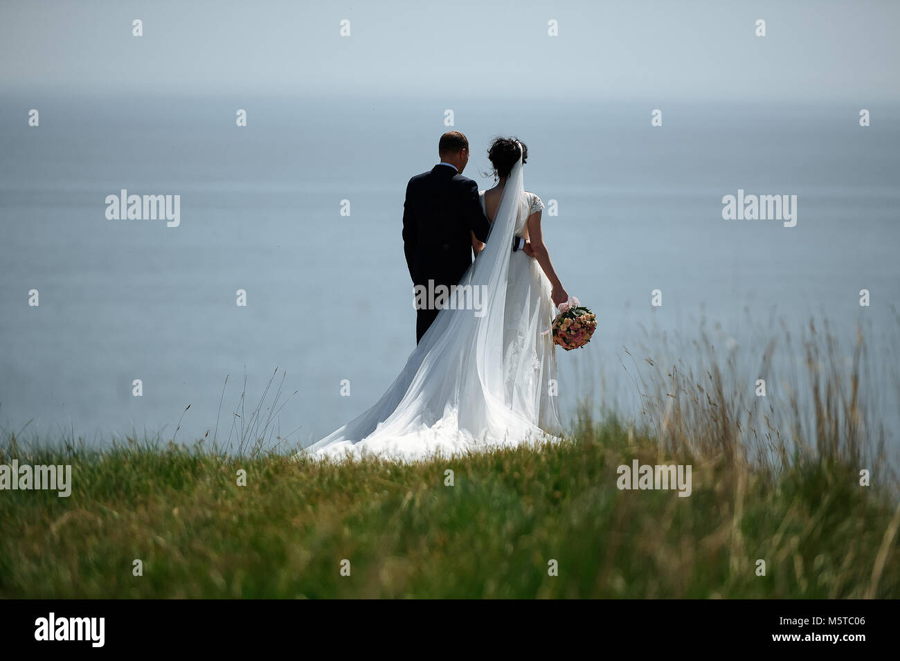 Wedding bride and groom at sea cliff back view Stock Photo - Alamy