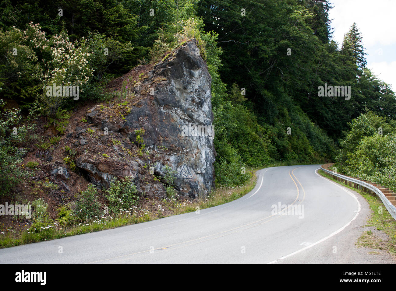 Curvy highway bending around a rocky corner with trees Stock Photo - Alamy