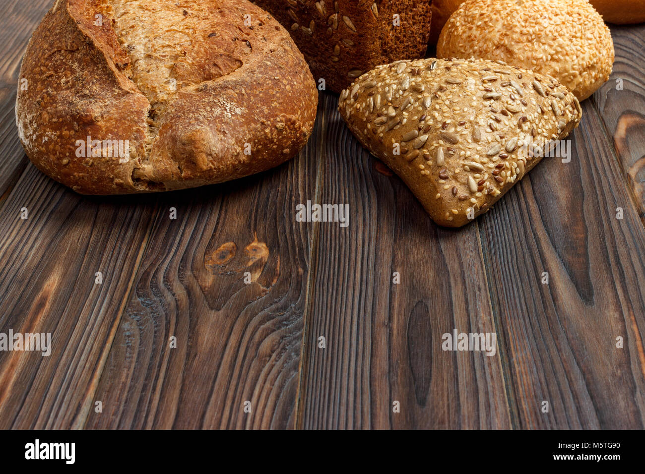 Assortment of baked bread on dark wooden background. Bakery and grocery ...