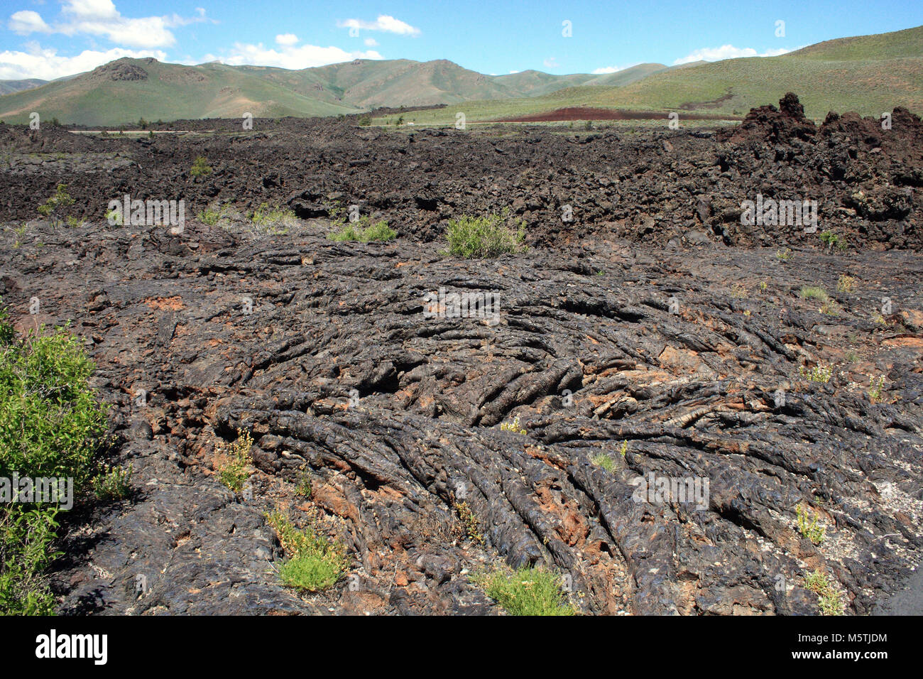A cinder butte rises above a huge lava flow at Craters of the Moon ...