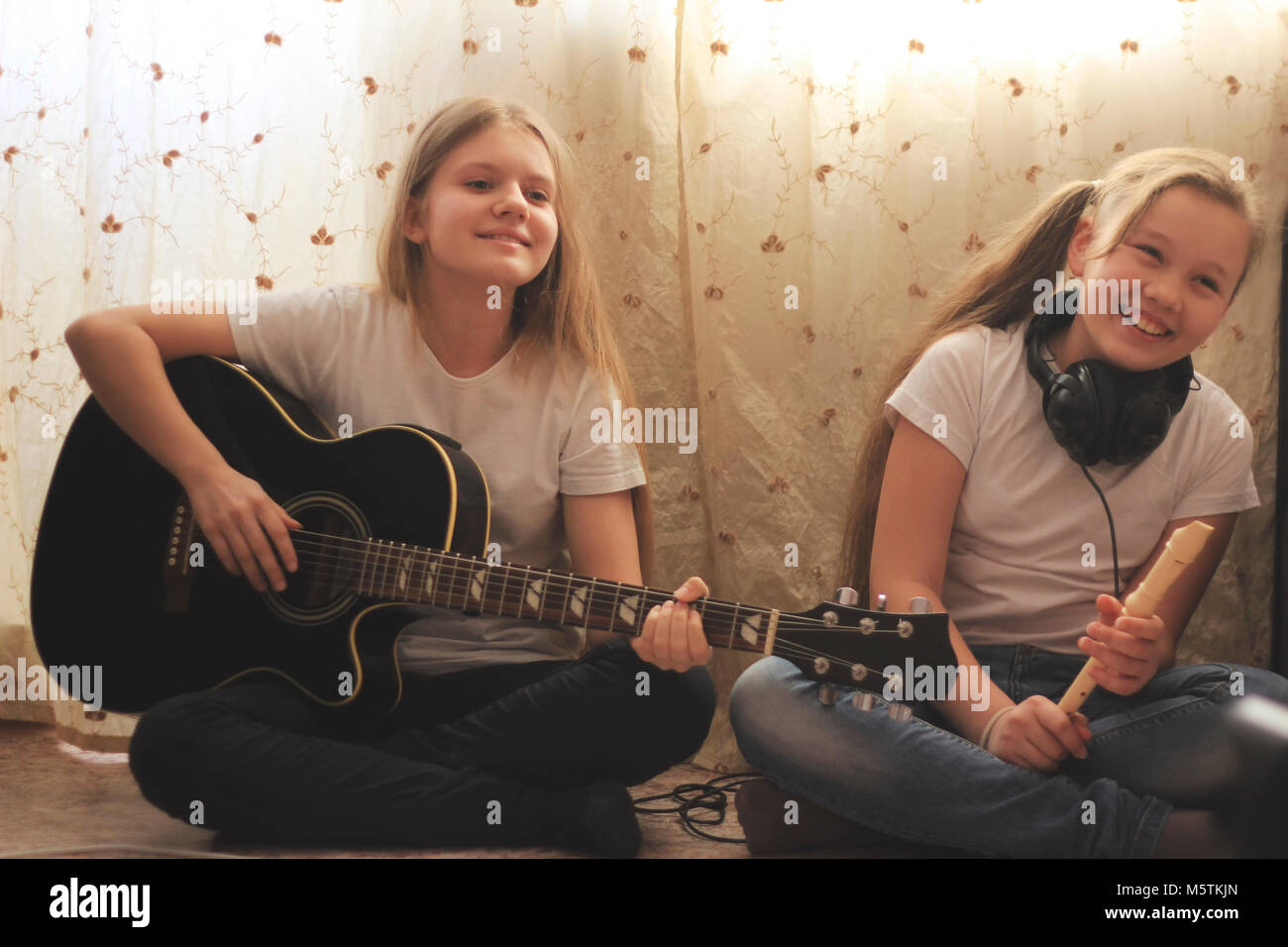 Two female teens playing musical instruments at home Stock Photo - Alamy