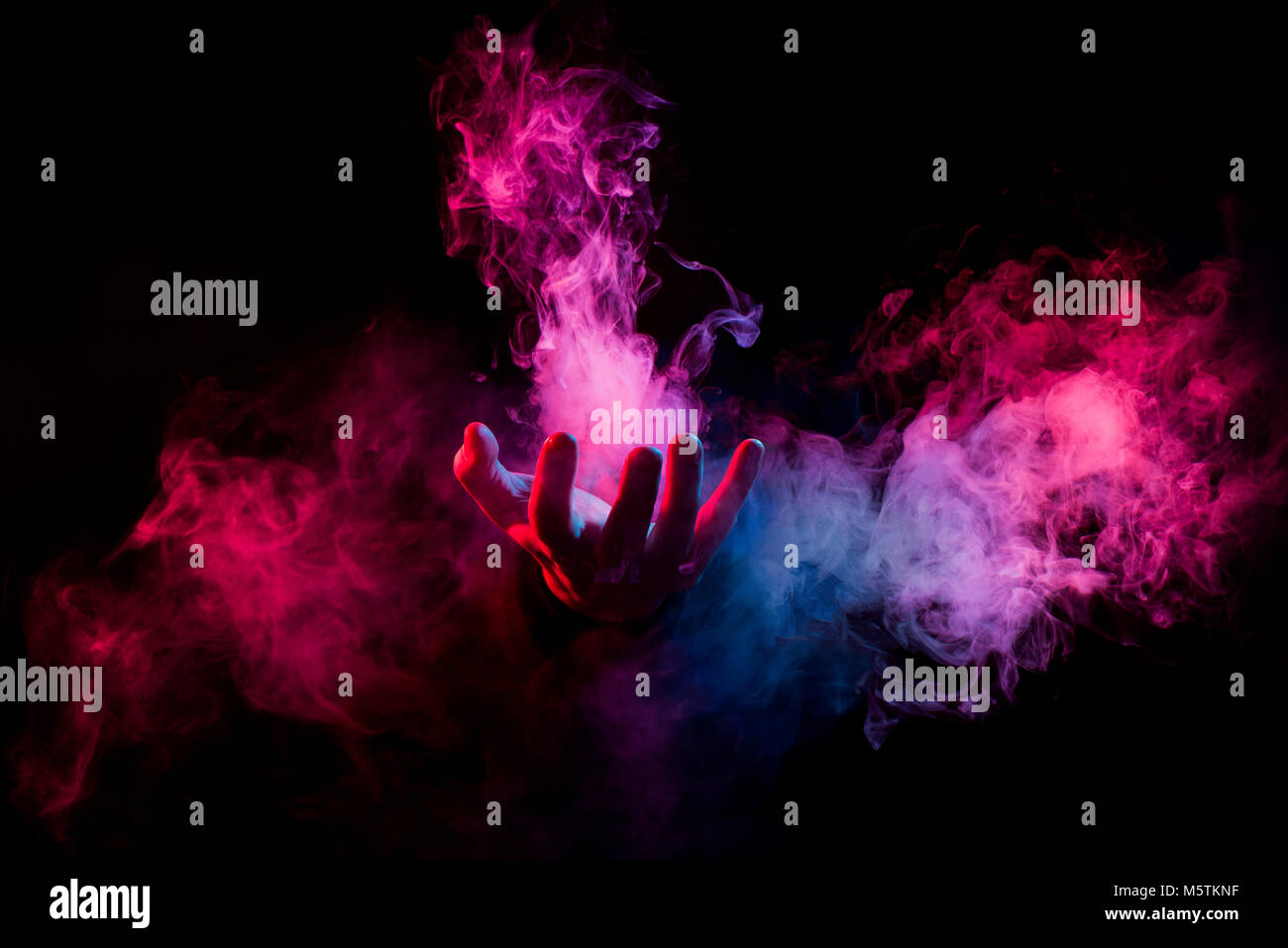 hand inside colorful smoke on black background Stock Photo - Alamy