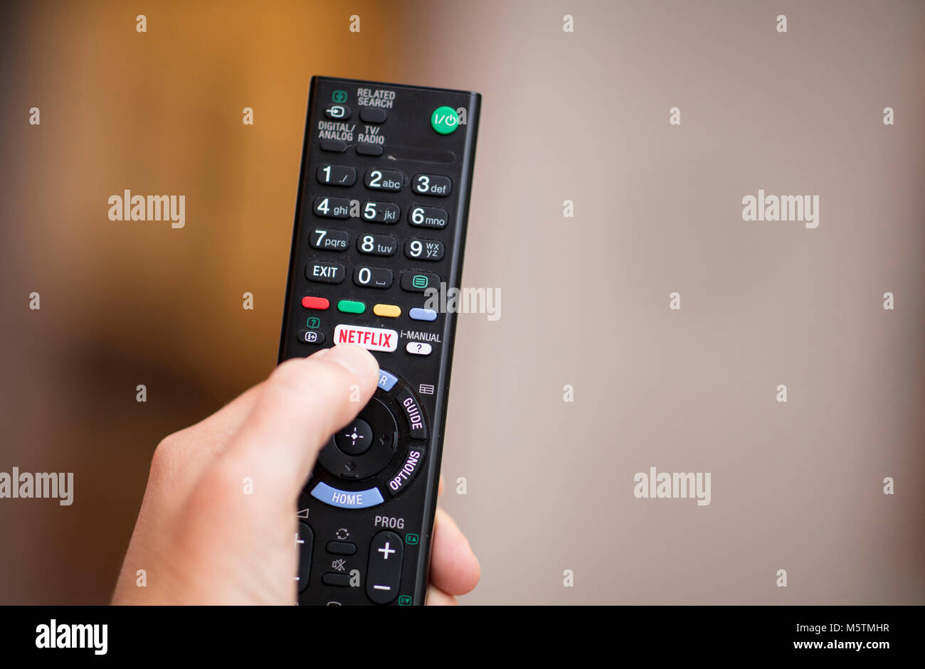 A person using a television remote with a dedicated Netflix logo on the ...