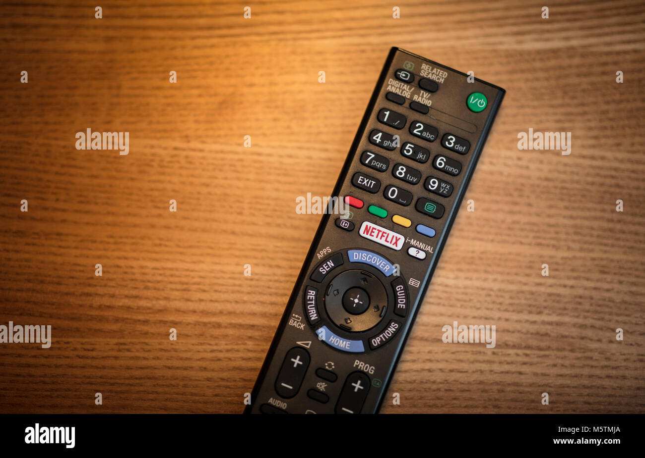 A person using a television remote with a dedicated Netflix logo on the ...
