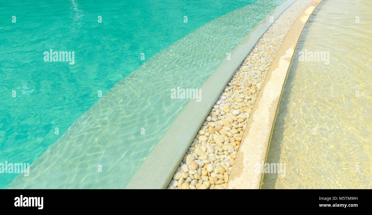 Closeup of stone border in front of bright blue swimming pool ...