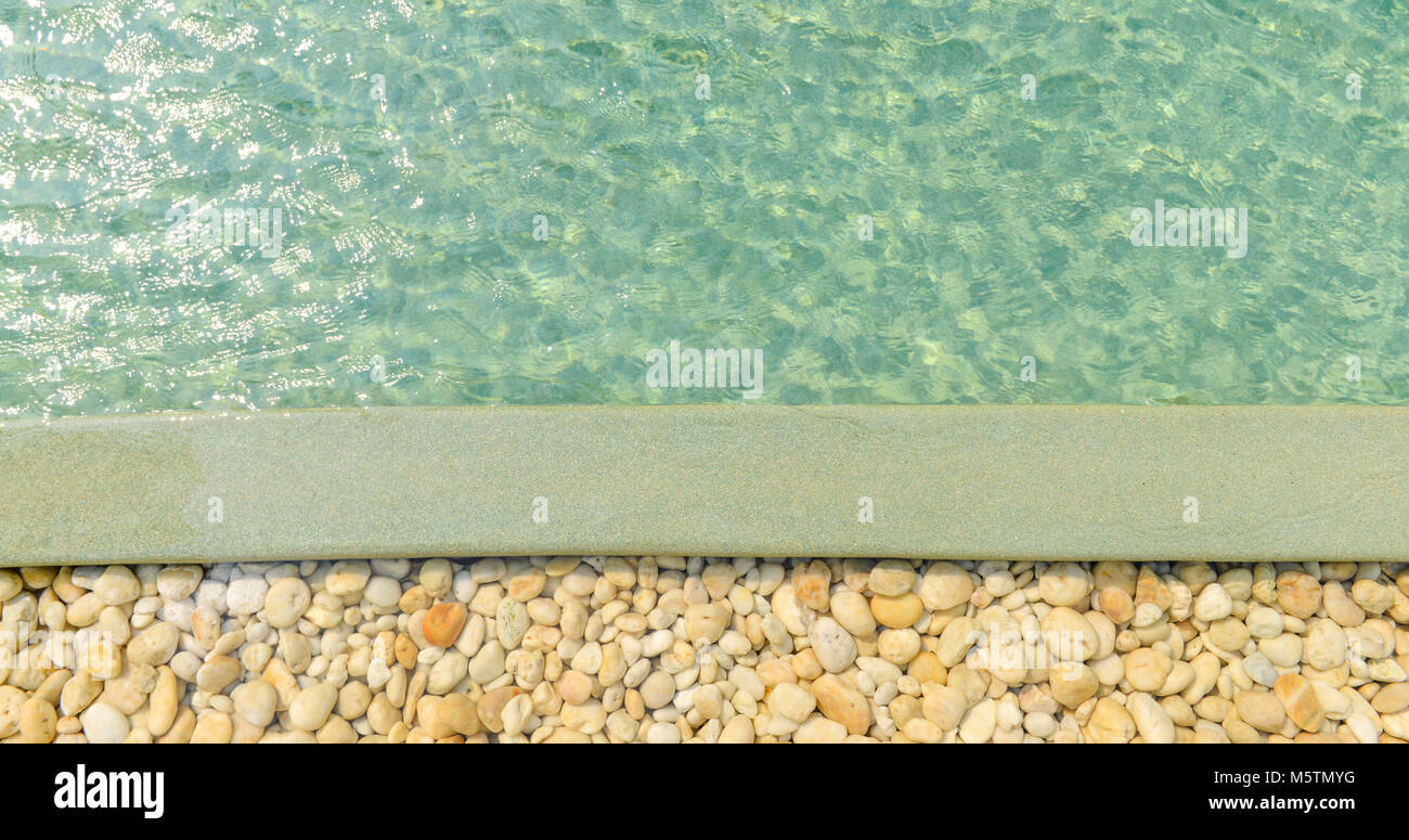 Closeup of stone border in front of bright blue swimming pool ...