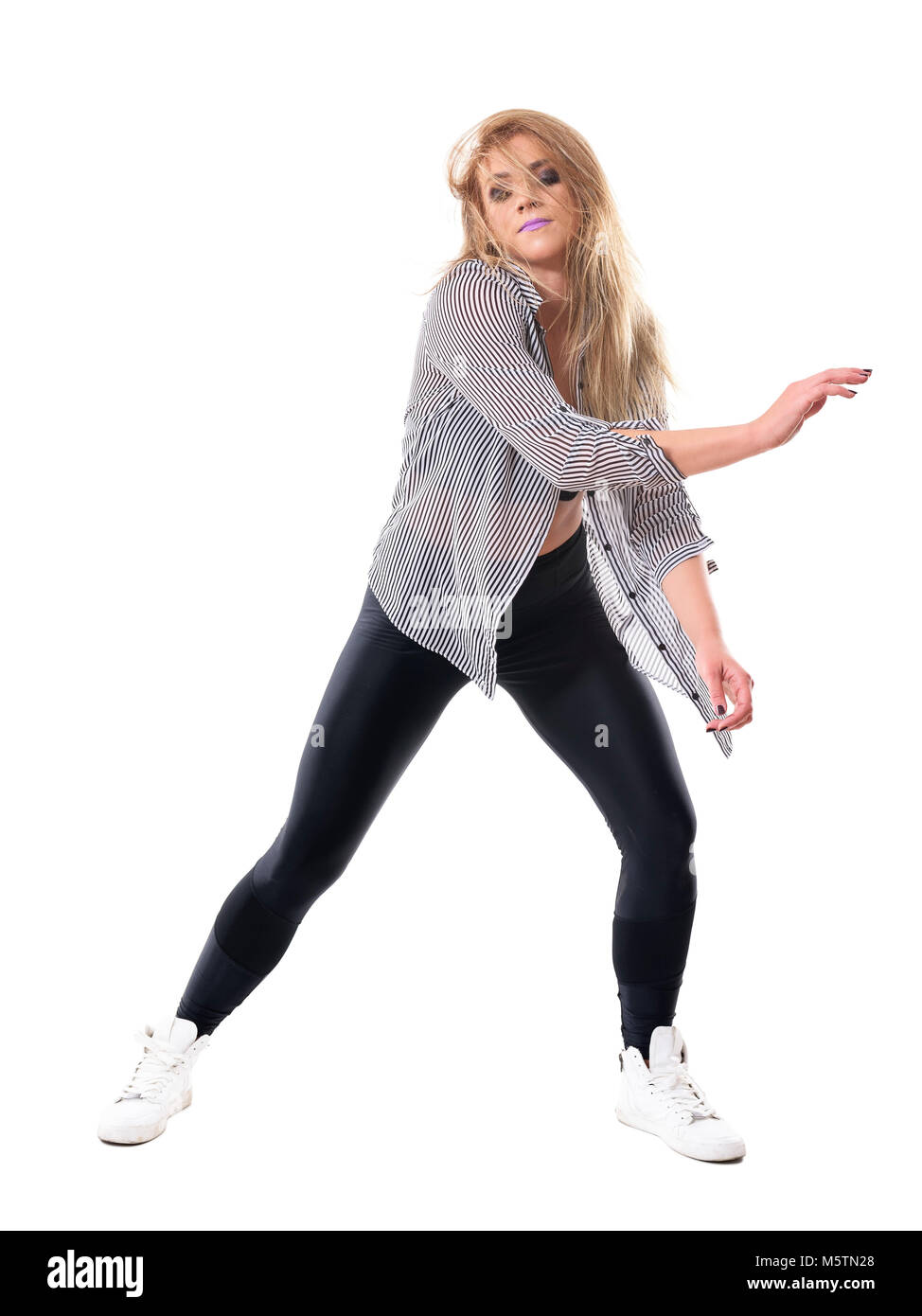 Active passionate blonde woman dancing jazz dance in unbuttoned striped ...