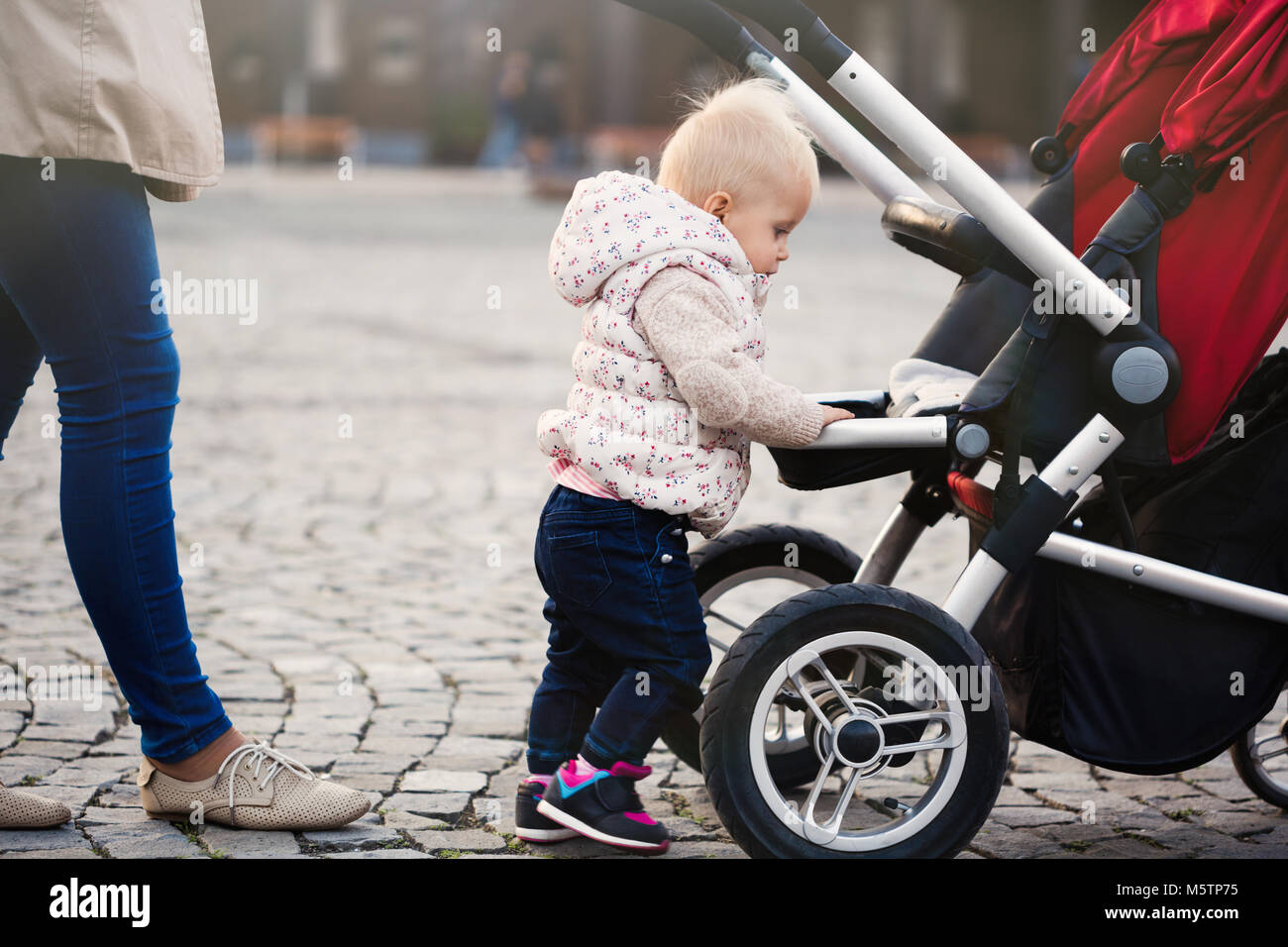 Beautiful toddler girl playing with his stroller walking outdoors Stock ...