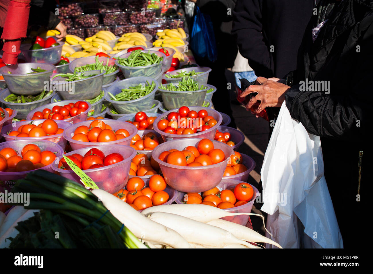 Female consumer at an open street market shopping fruit and vegetables ...