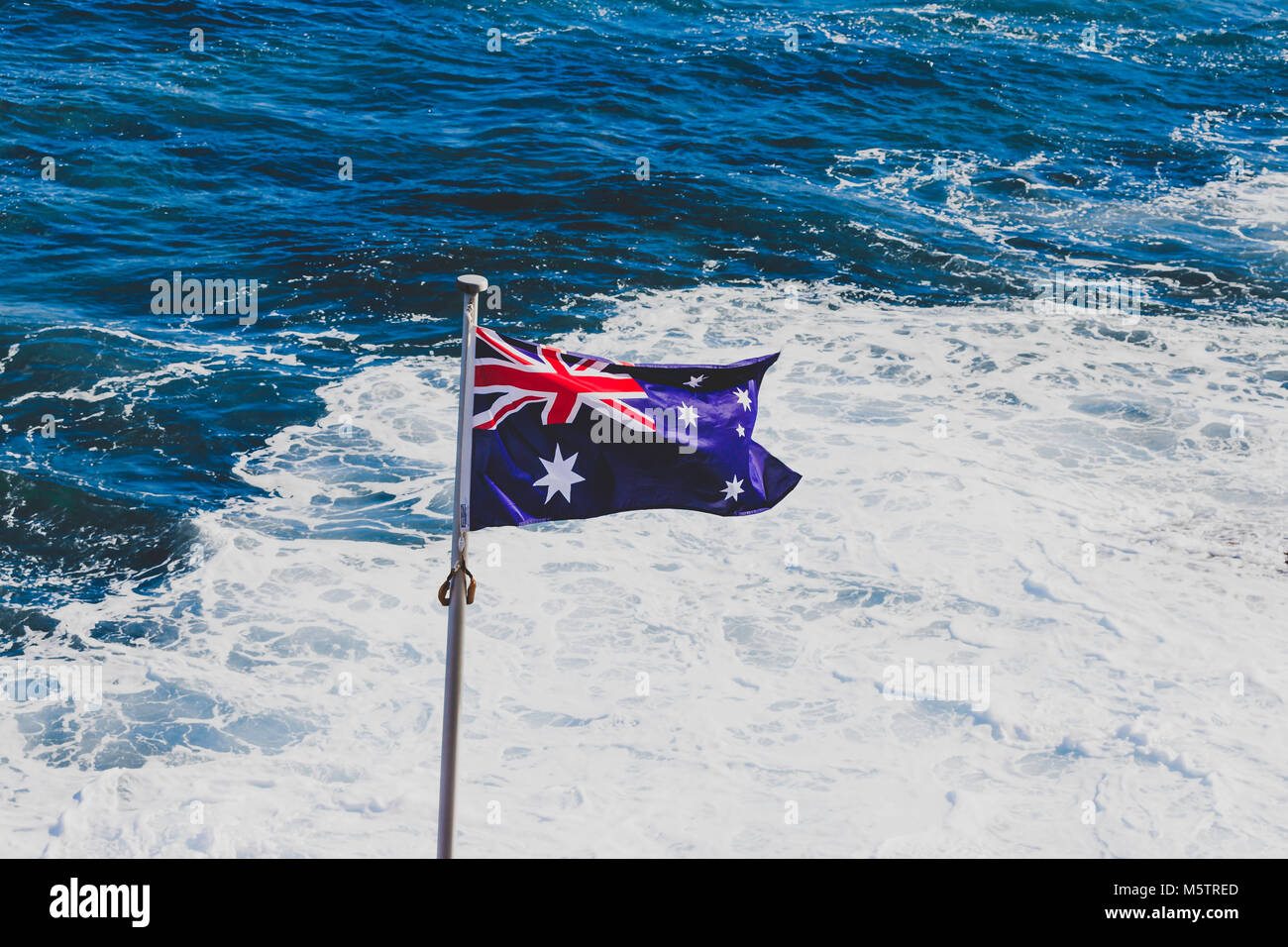 Australian flag waving in front of big ocean waves in Bondi Beach ...