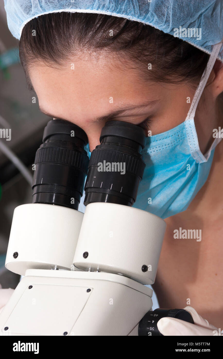 Medical professional looking through a microscope Stock Photo - Alamy