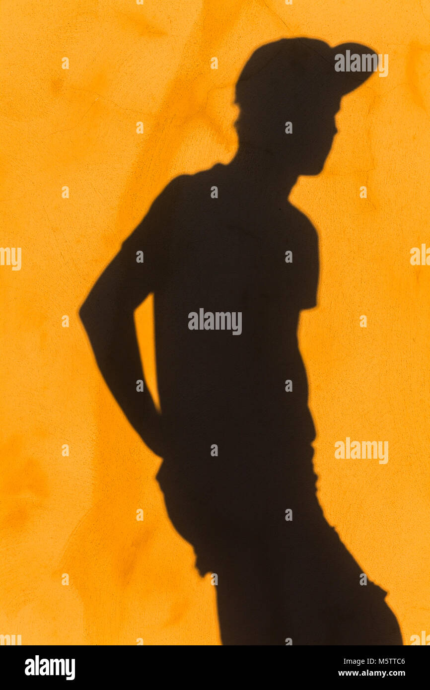 Teenager boy's shadow on yellow textured wall with attitude abstract ...