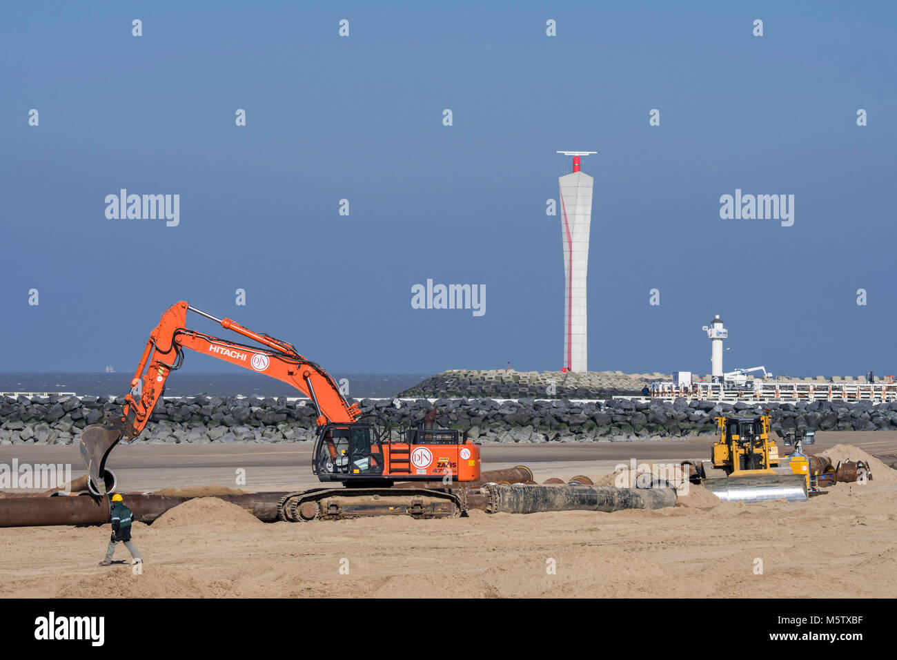Bulldozer and hydraulic excavator installing pipeline during sand ...