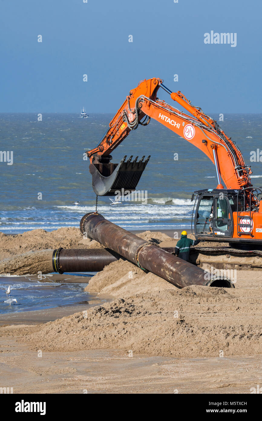 Hydraulic excavator installing pipeline during sand replenishment ...