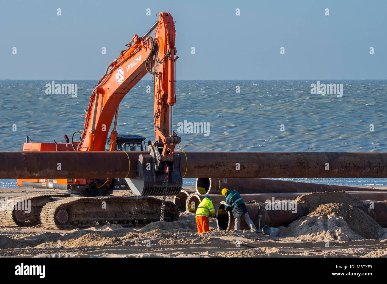 Dredging workers connecting pipes of pipeline during sand replenishment ...