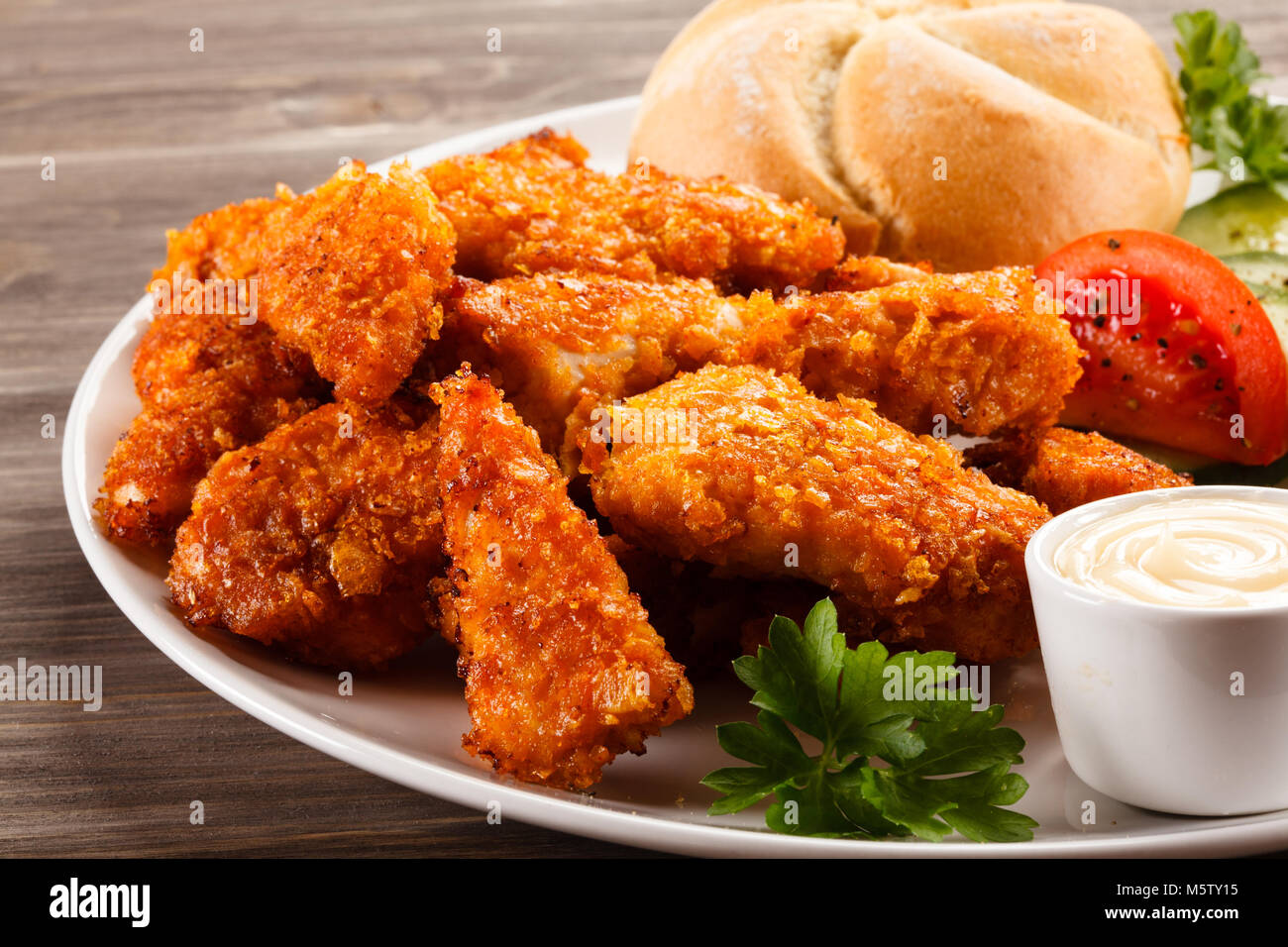 Grilled chicken nuggets and vegetables on wooden table Stock Photo - Alamy