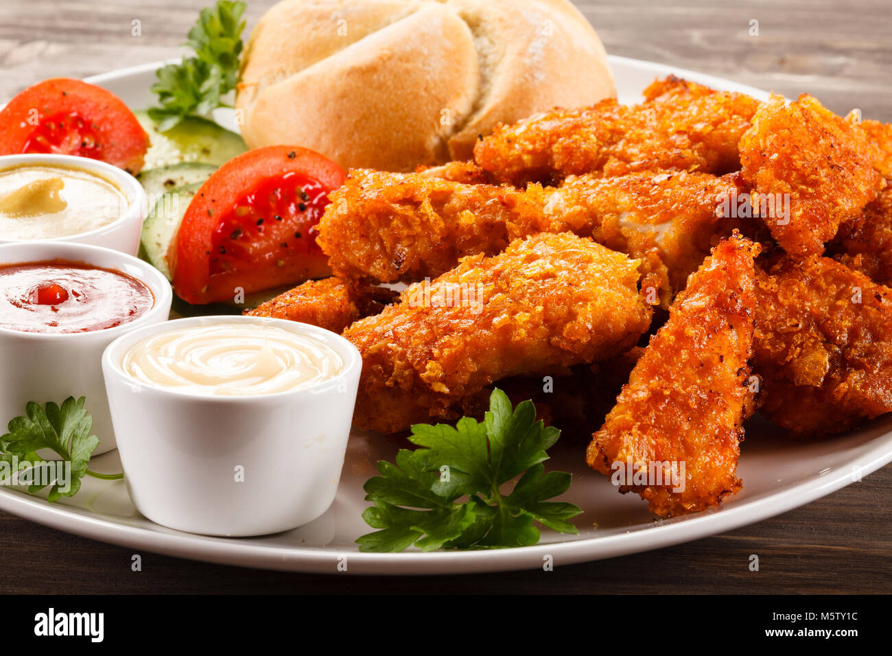 Grilled chicken nuggets and vegetables on wooden table Stock Photo - Alamy