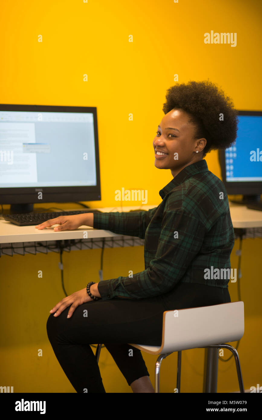 a young black international student is photographed using a computer in ...