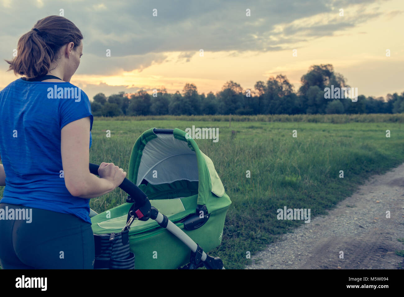 Active mom pushing a stroller at sunset Stock Photo - Alamy