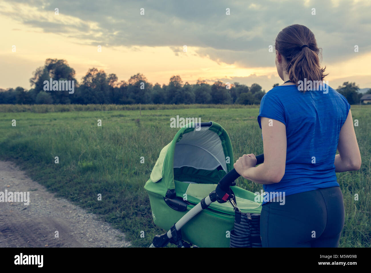 Active mom pushing a stroller at sunset Stock Photo - Alamy