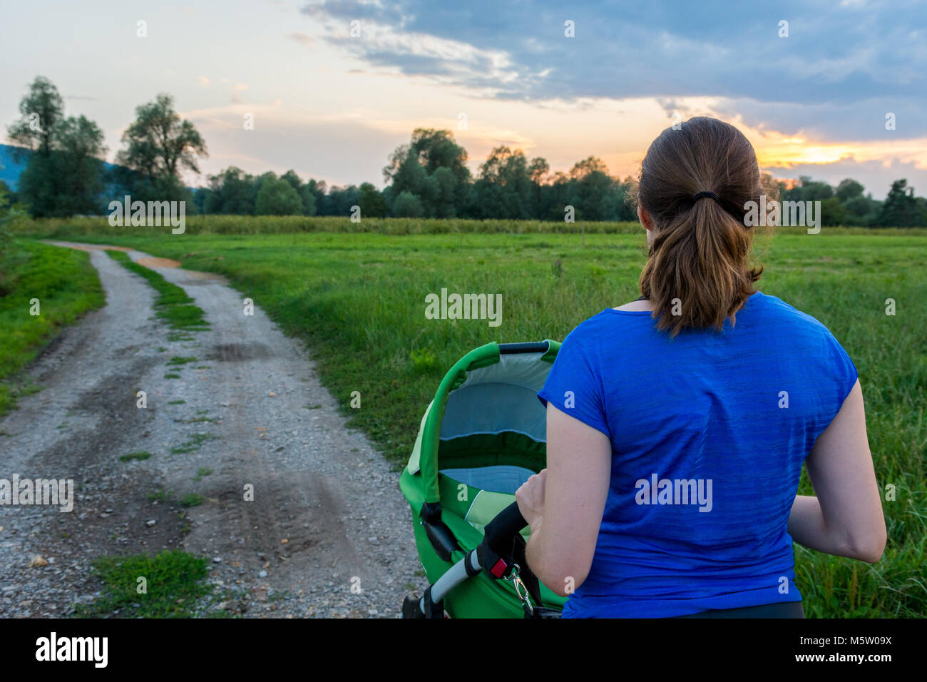 Active mom pushing a stroller at sunset Stock Photo - Alamy