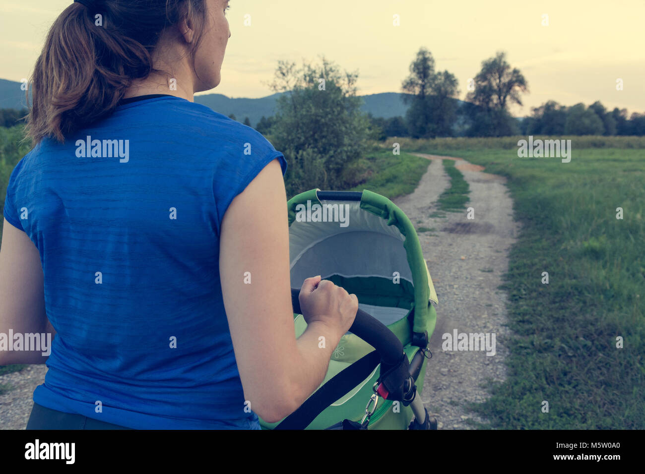 Active mom pushing a stroller at sunset Stock Photo - Alamy