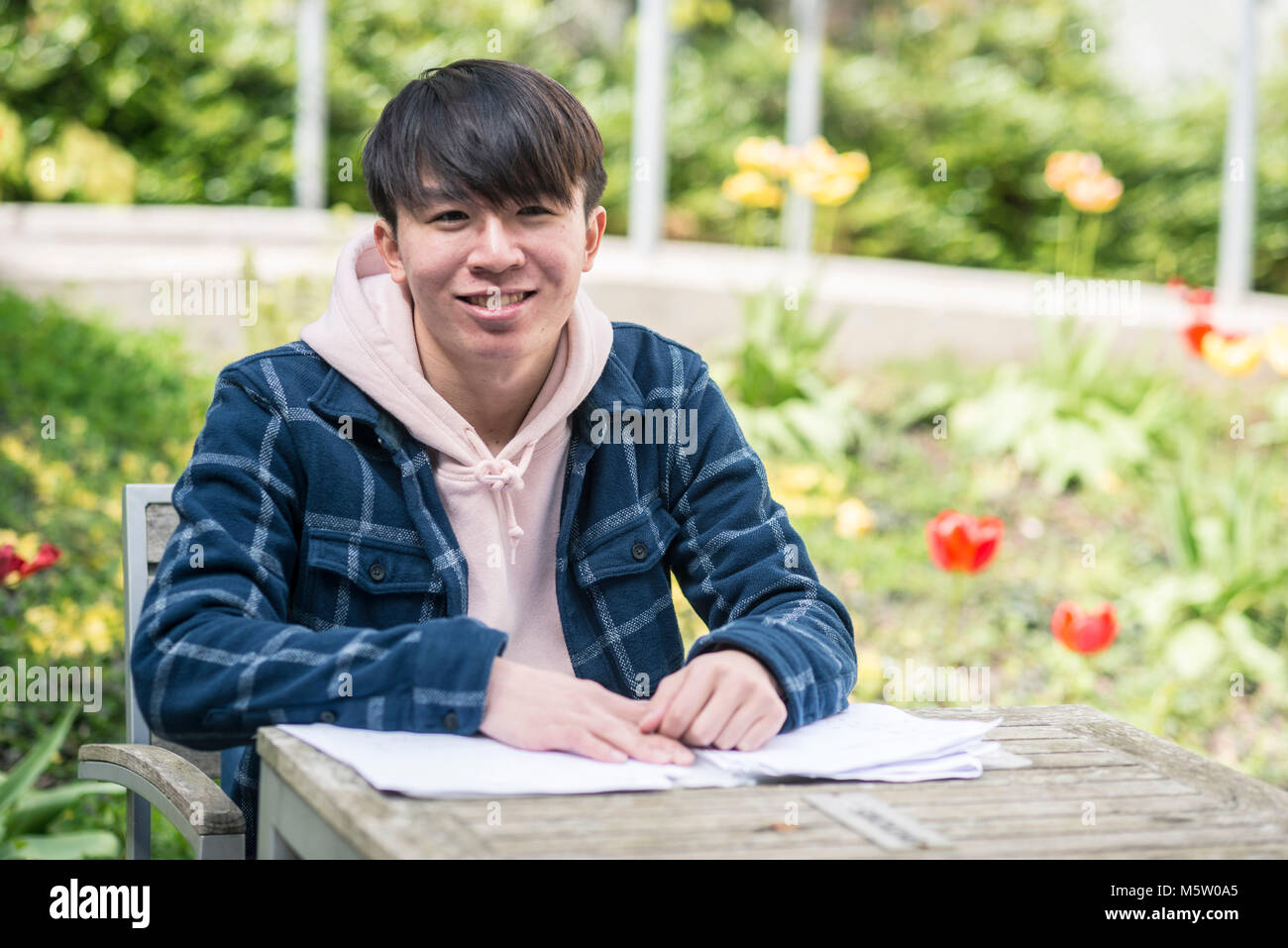 a young asian international overseas student sits around the college ...