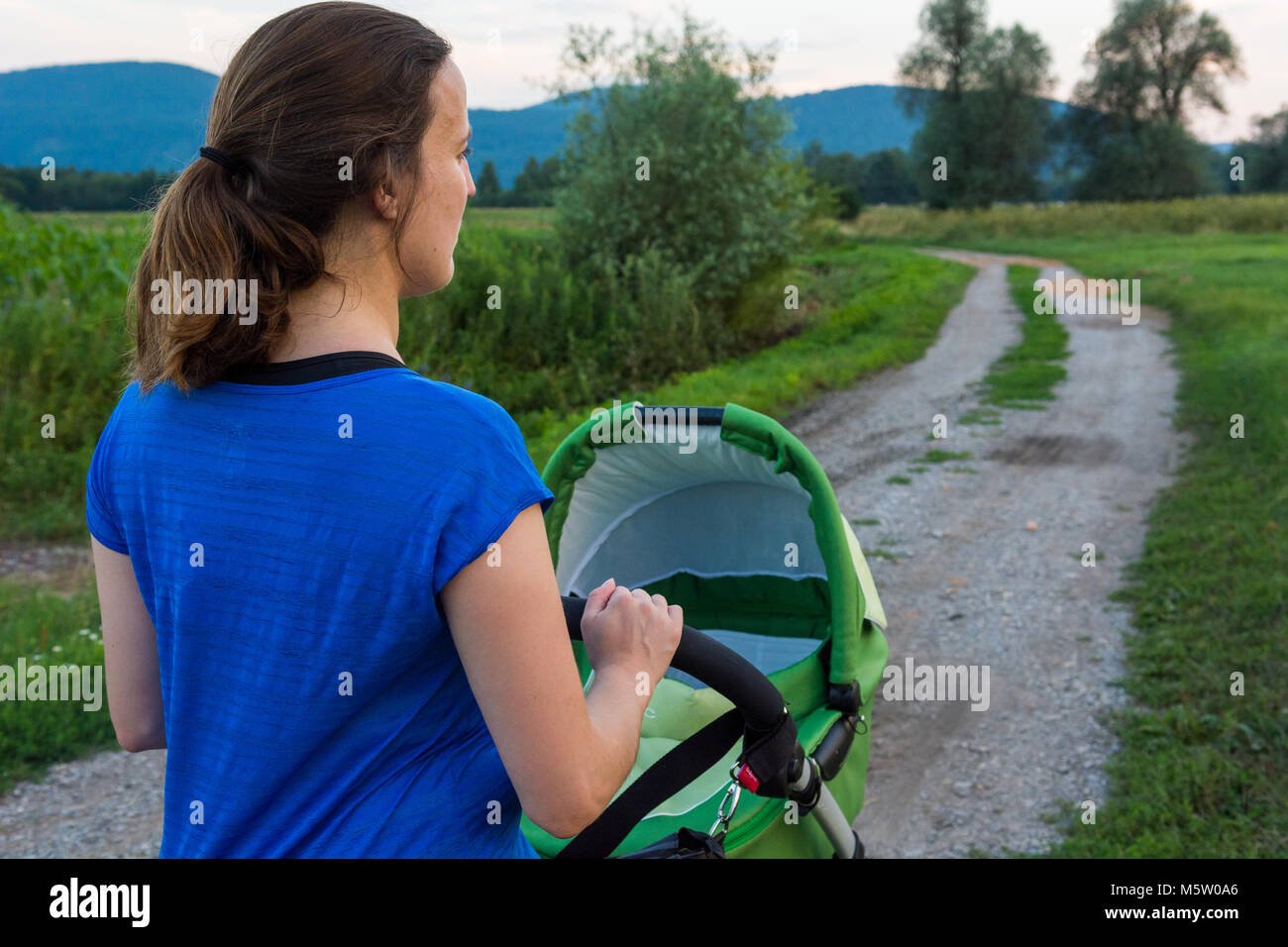 Active mom pushing a stroller at sunset Stock Photo - Alamy